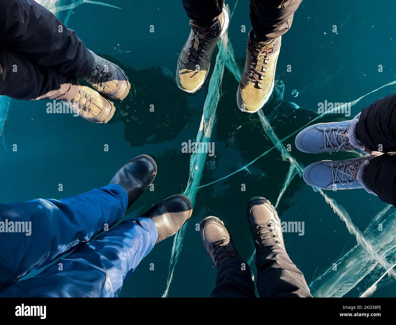Fragile thin brittle ice underfoot. Male and female feet on ice. People ...