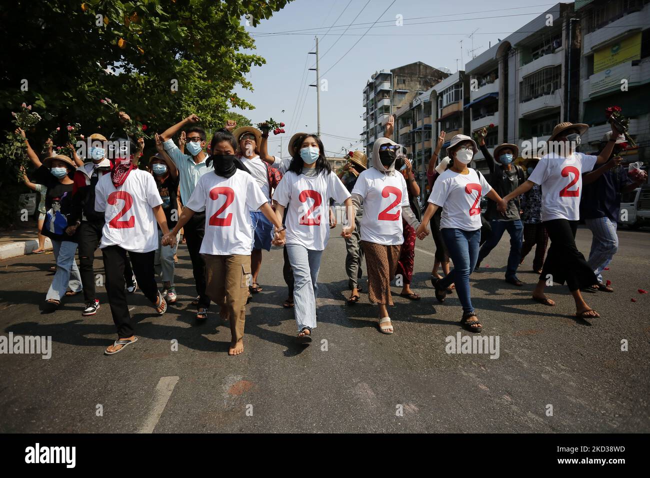 Demonstrators make the defiant three-finger salute and hold roses as ...