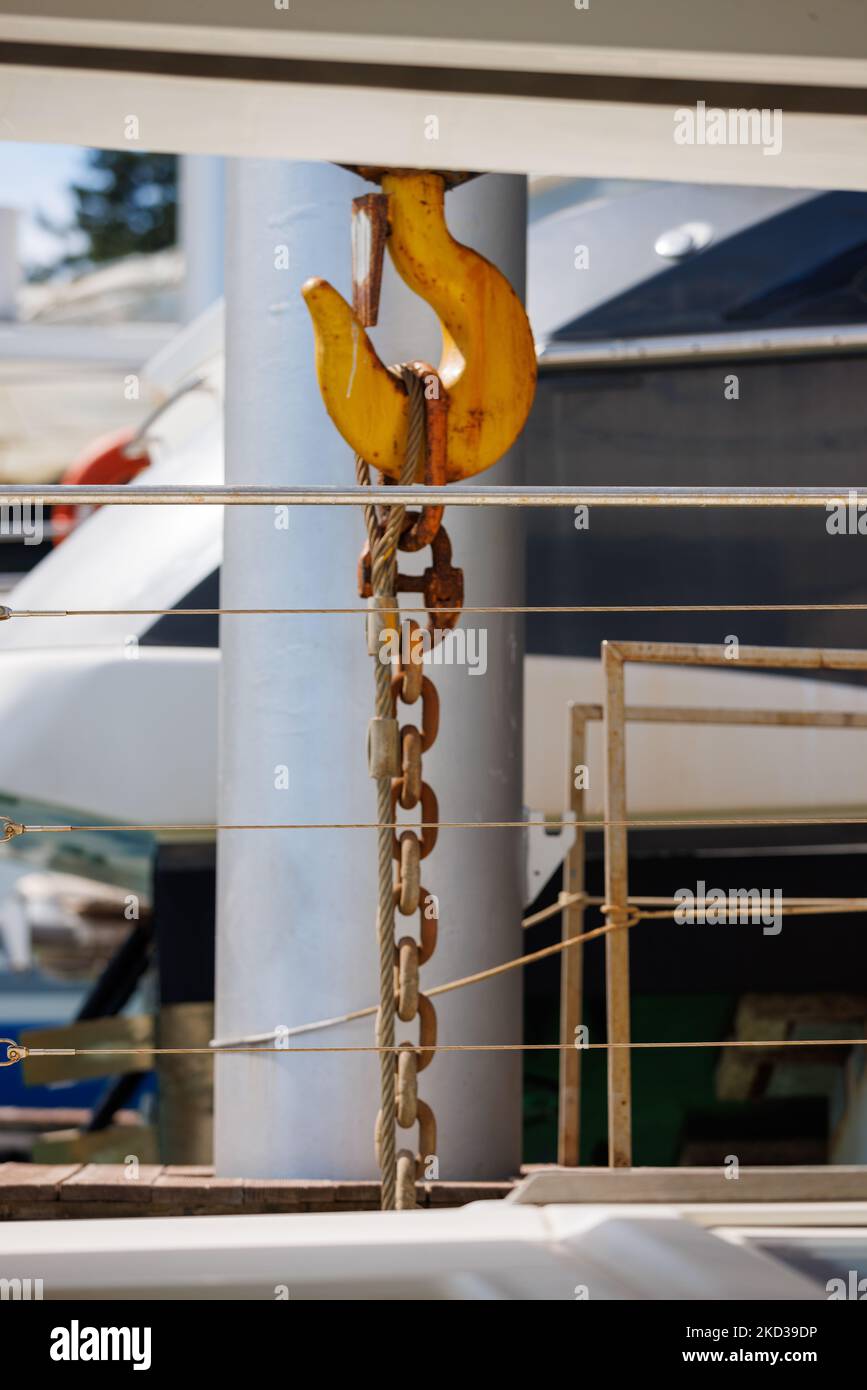 A vertical of an orange thick rusted chain suspended by a yellow hook ...