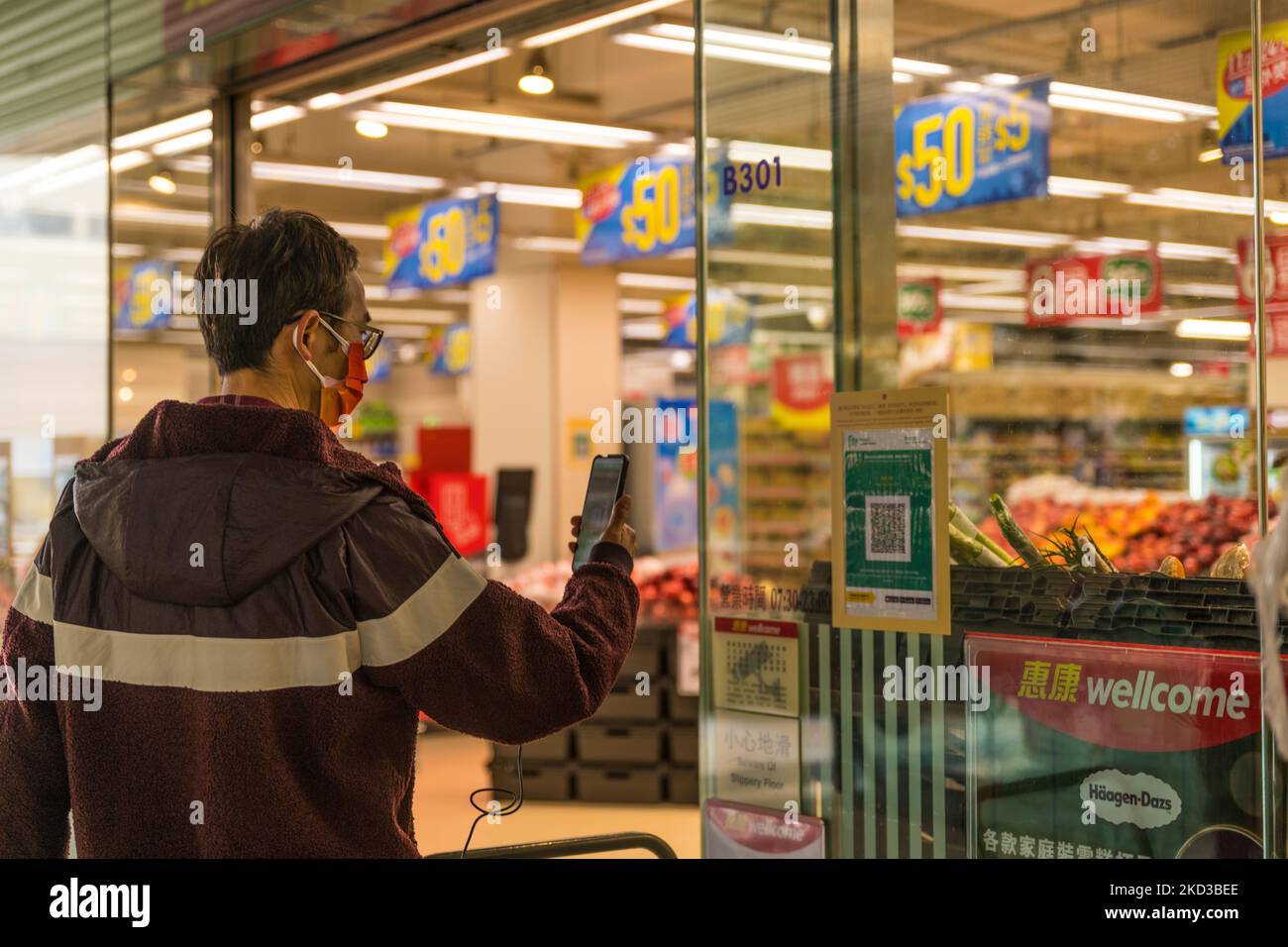 A man scans the Leave Home Safe QR code outside a supermarket, in Hong ...