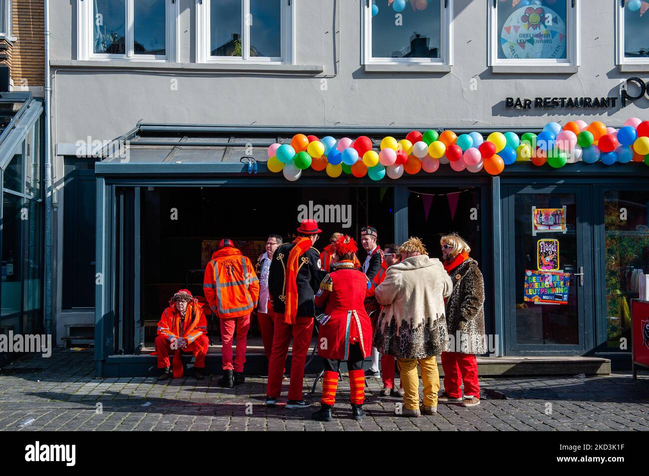 People wearing orange costumes are already drinking outside of a pub ...