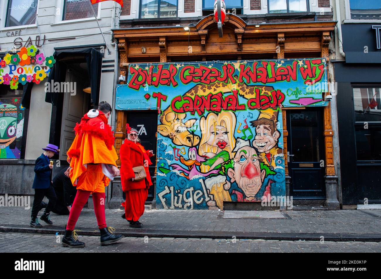 A family wearing costumes is passing by in front of a graffiti that ...