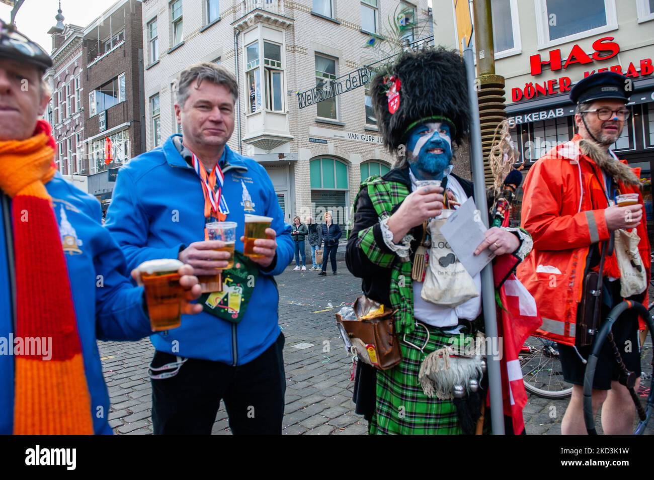 A group of men is wearing different costumes while holding beers ...
