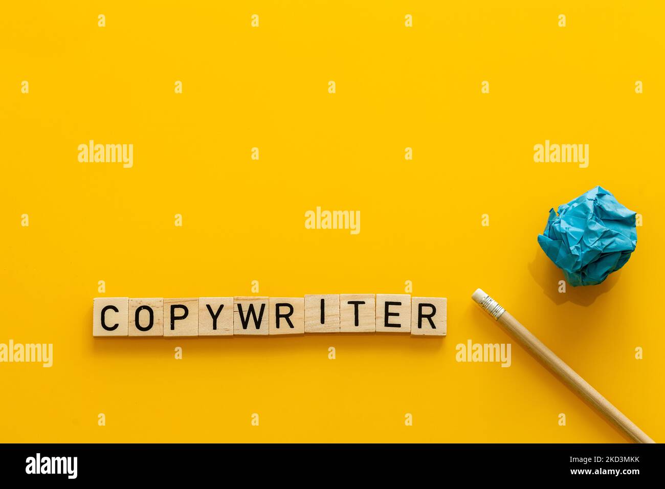 Word copywriter on wooden plates next to a pencil and blue crumpled ...