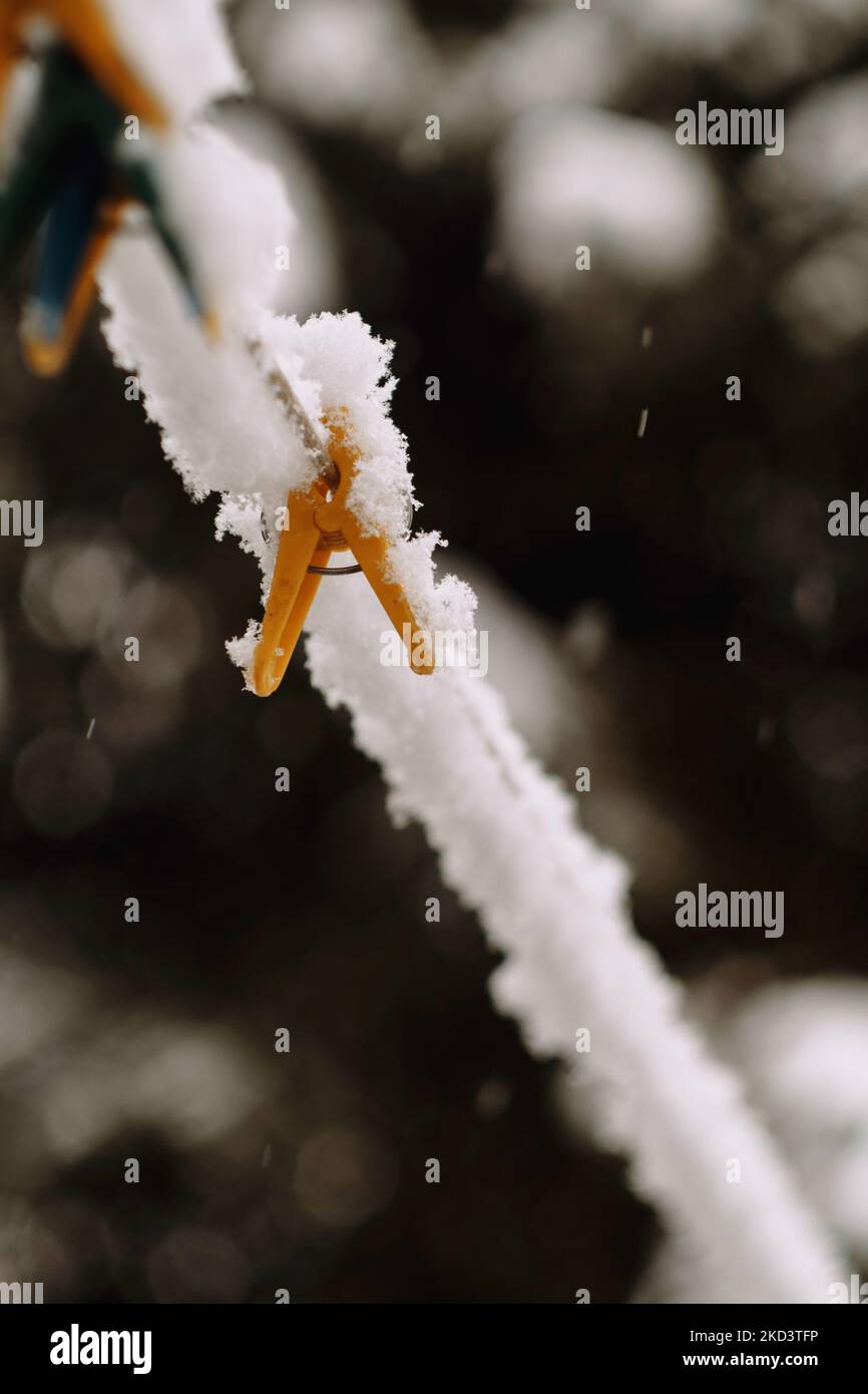 A vertical shallow focus shot of colorful clothespins covered in frost ...
