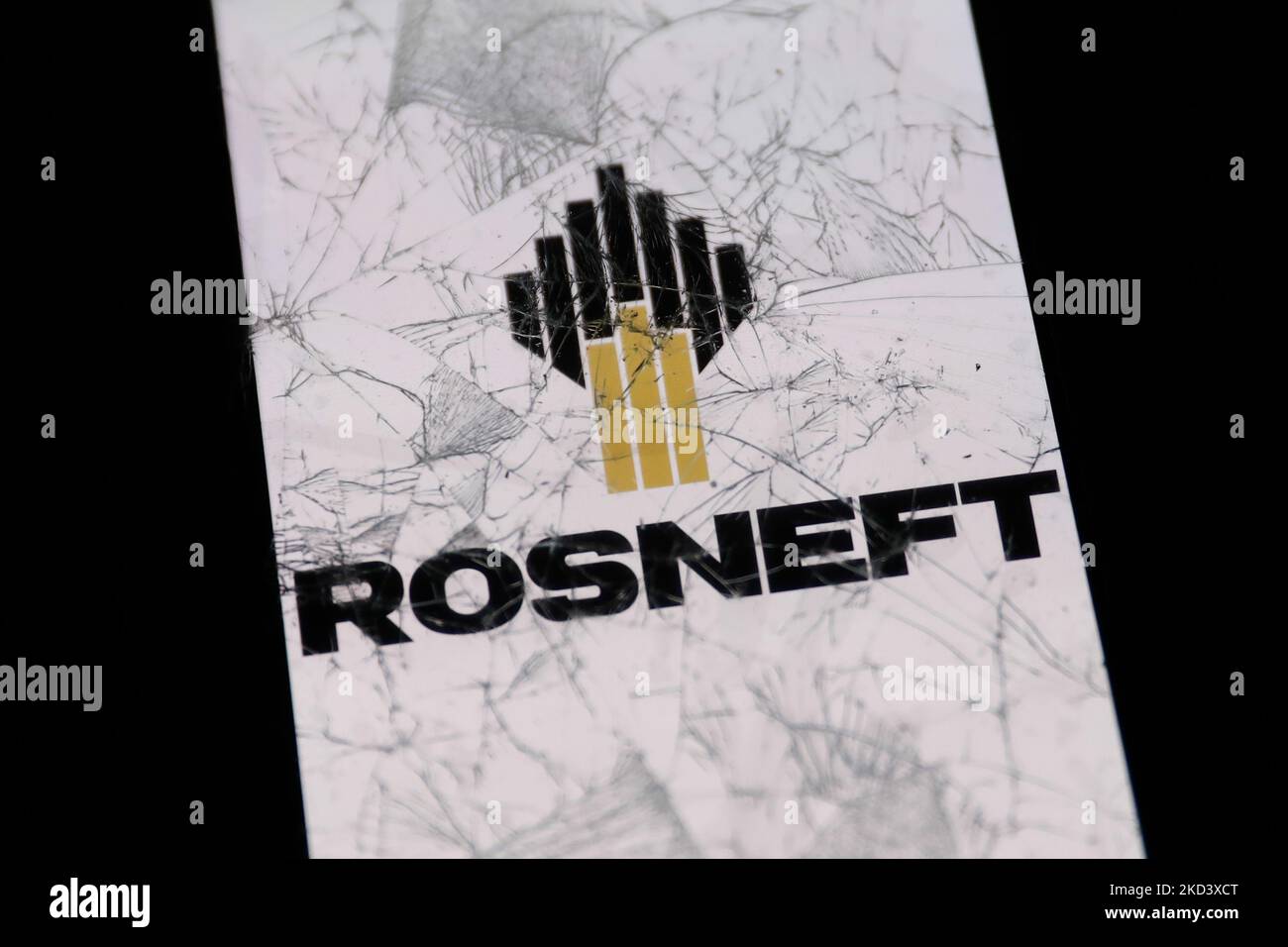 Rosneft logo displayed on a phone screen is seen through a broken glass ...