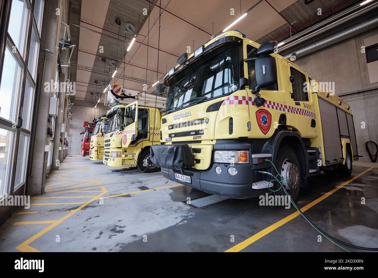 A yellow fire truck in the garage of a Norwegian fire station with ...