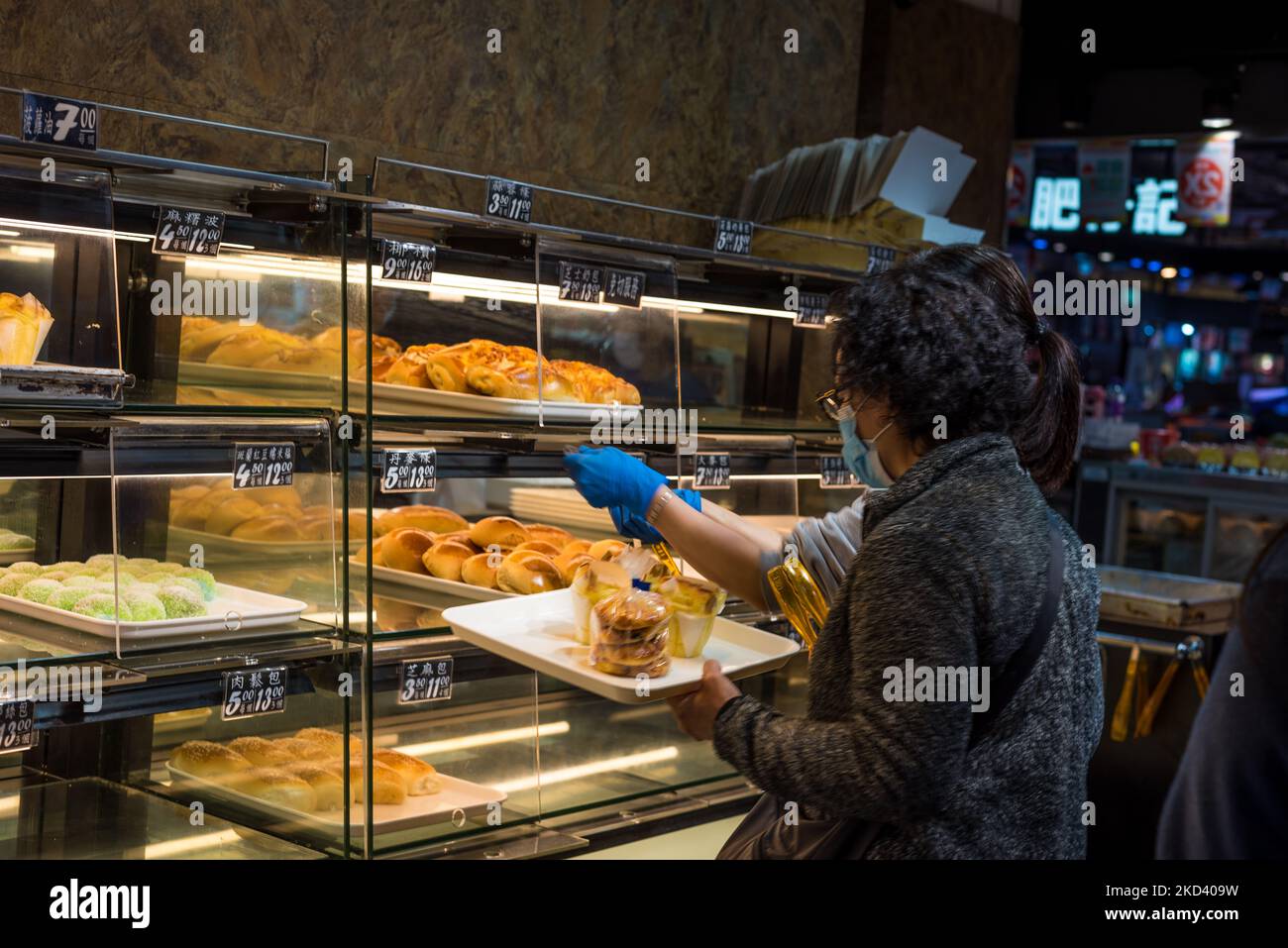 An elderly lady buys break at a bakery that is almost empty, in Hong ...