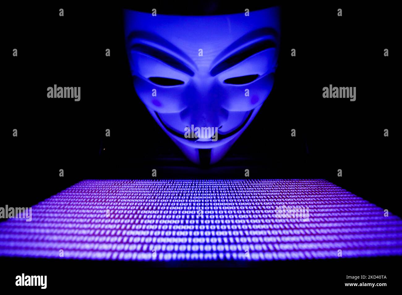 Binary code displayed on a laptop screen and Guy Fawkes mask are seen ...