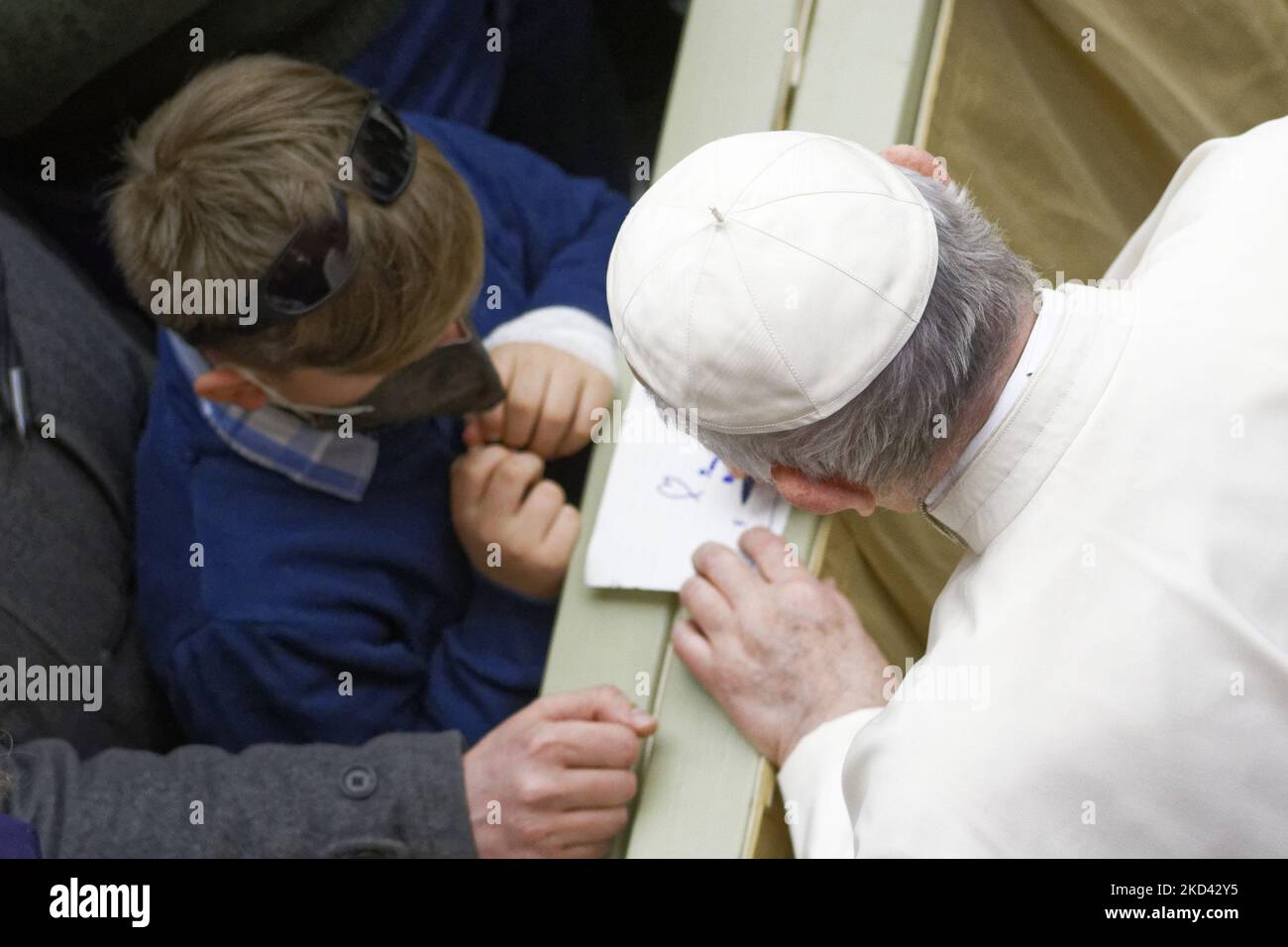 Pope Francis signs a piece paper for a child during his weekly general ...