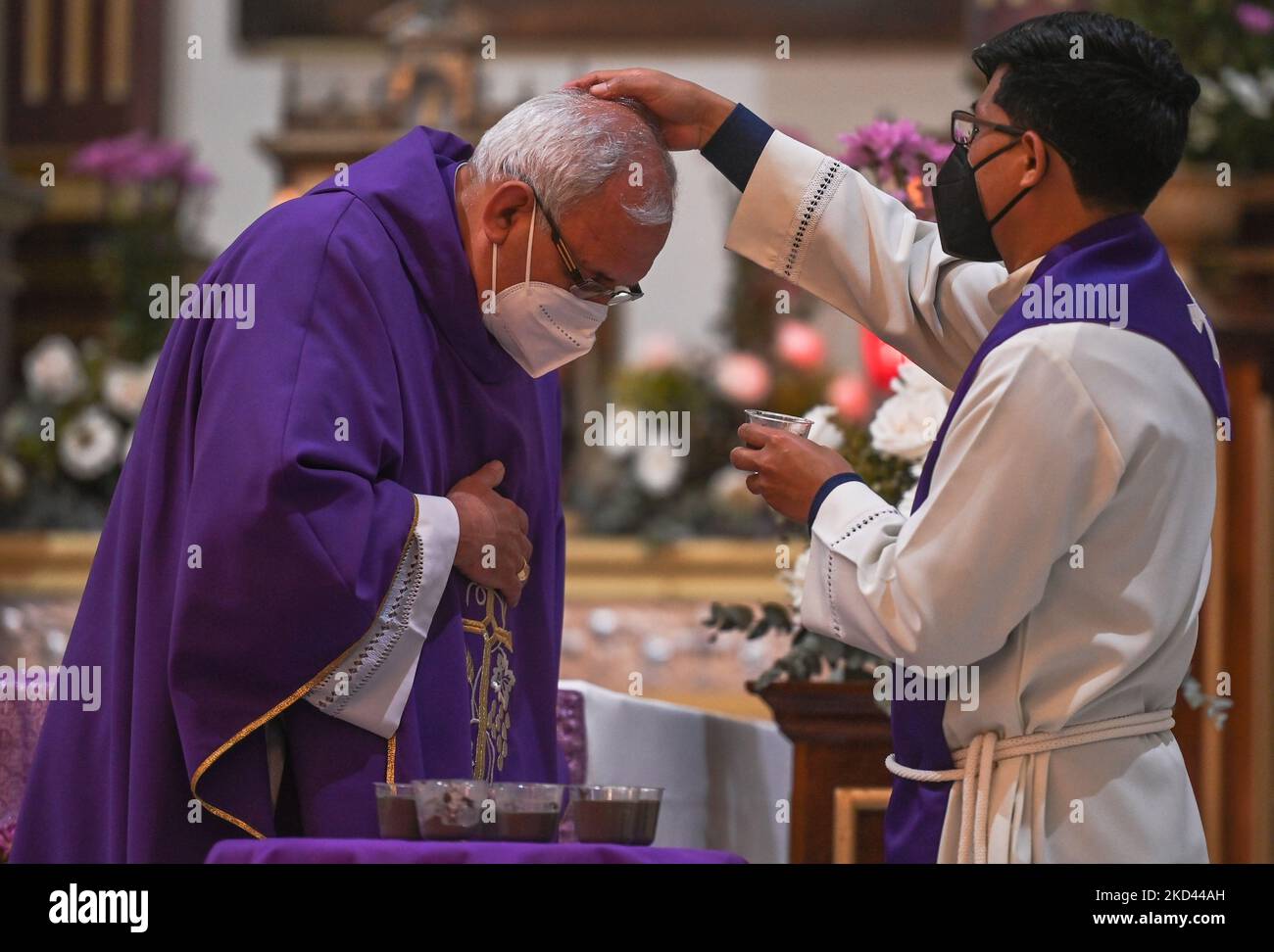 The priest makes the sign of the cross with ashes on the head of ...