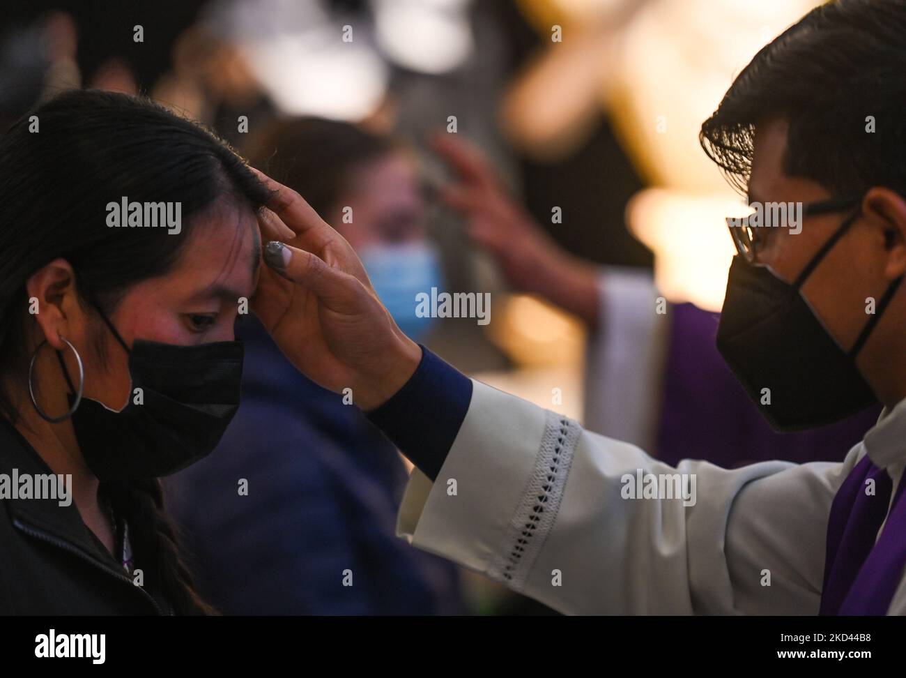 A priest makes the sign of the cross with ashes on the head of the ...