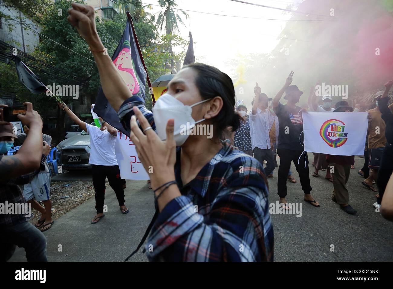 Demonstrators make the defiant three-finger salute and hold flares as ...