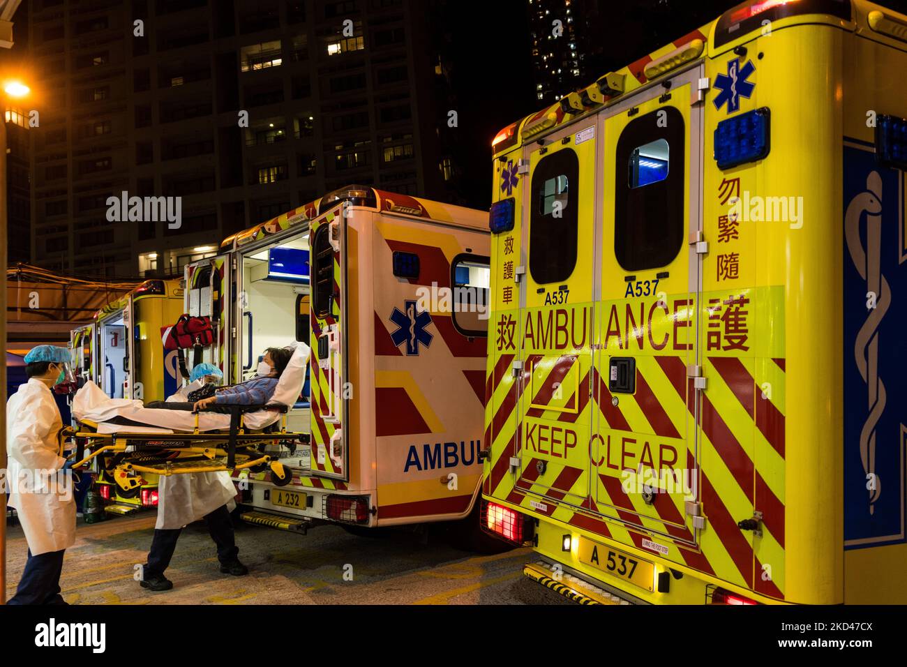 Paramedics in PPE unload a patient from an ambulance at United ...