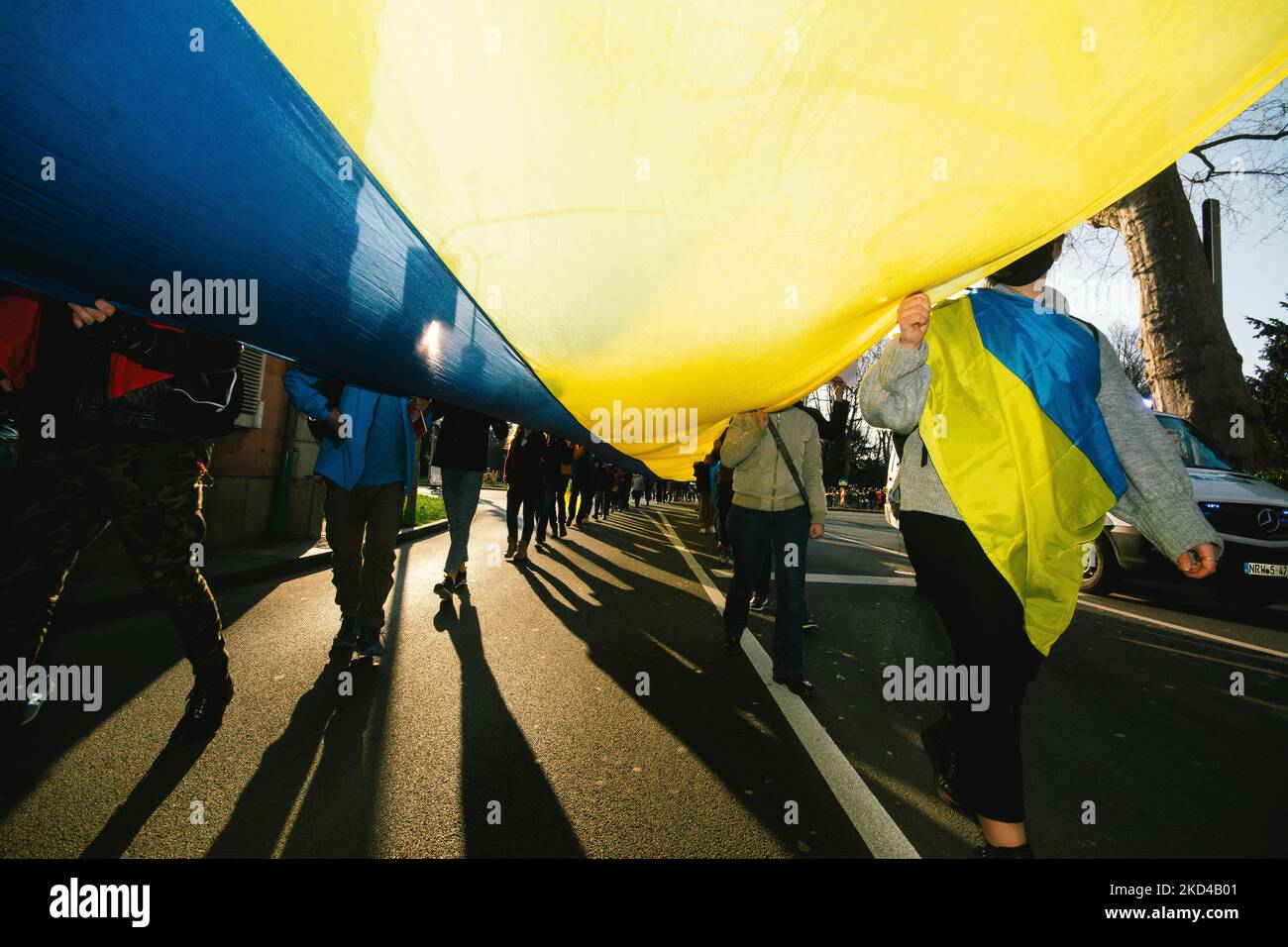 protesters hold up a giant Ukrainian flag during the anti war protest ...