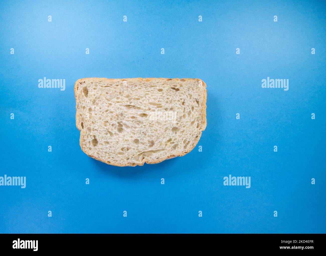 a single slice of fresh seeded bread isolated on a dark blue background ...