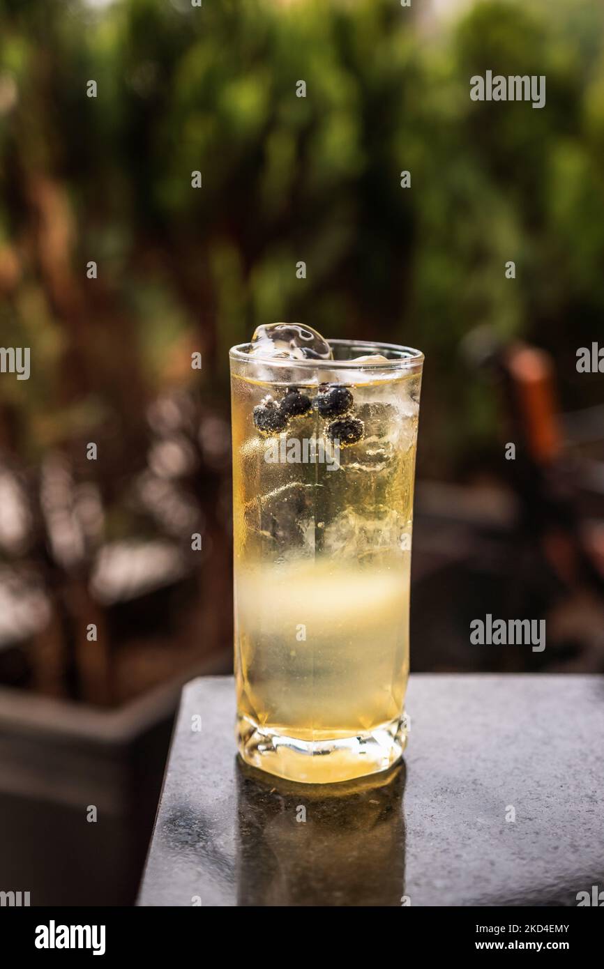 A transparent blueberry based alcoholic drink served at sunset on a ...