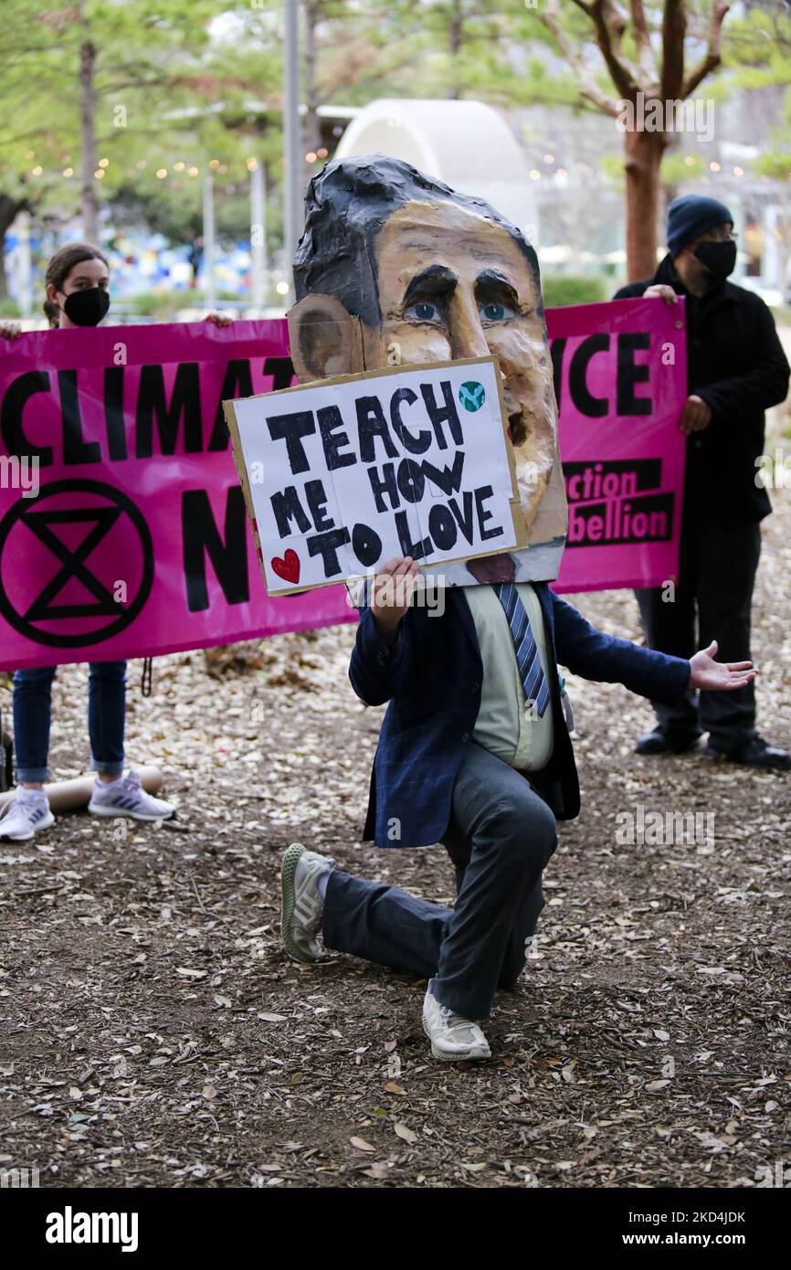 A climate activist wears a large John Kerry mask outside the CERAweek ...