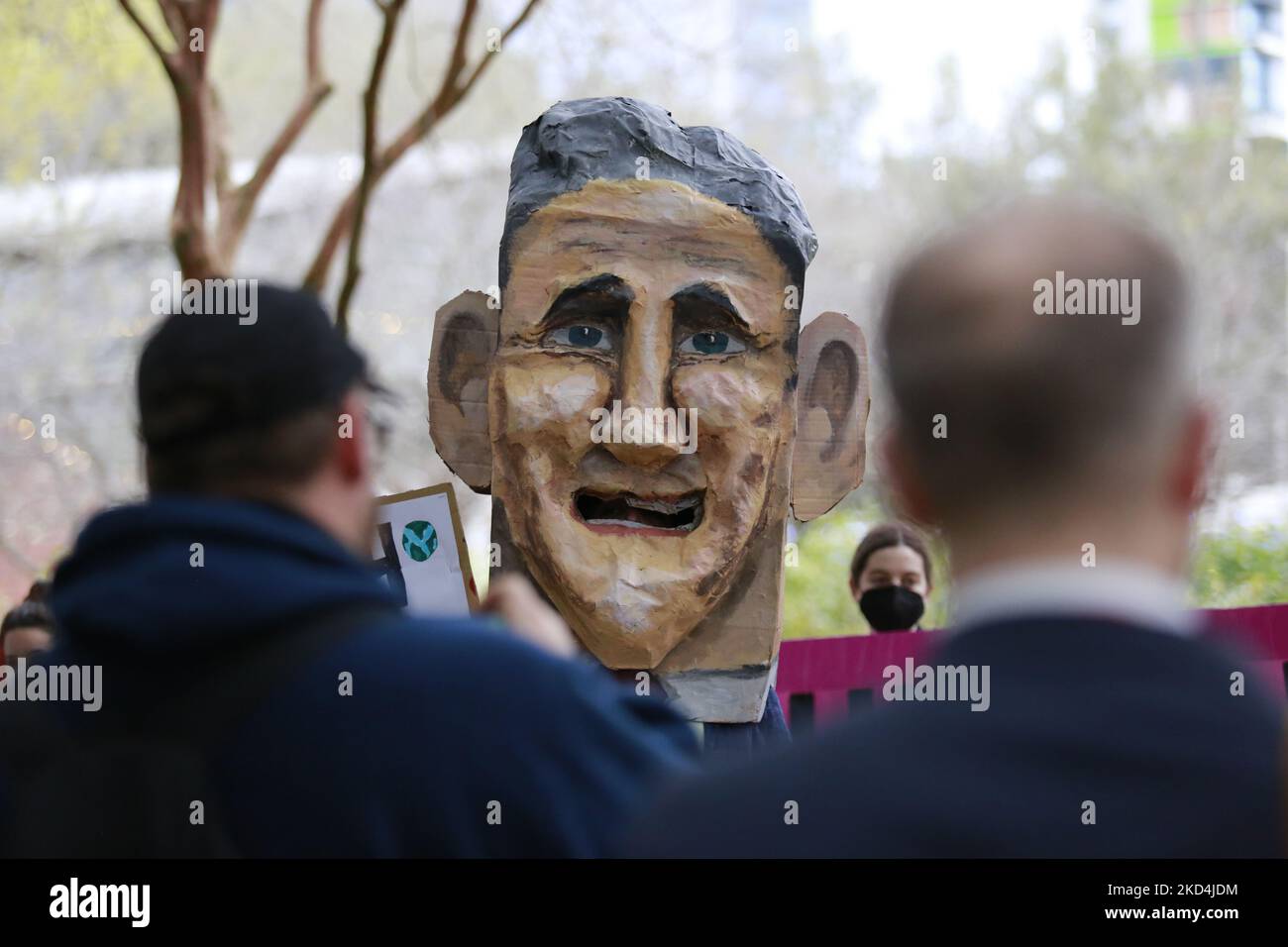 A climate activist wears a large John Kerry mask outside the CERAweek ...
