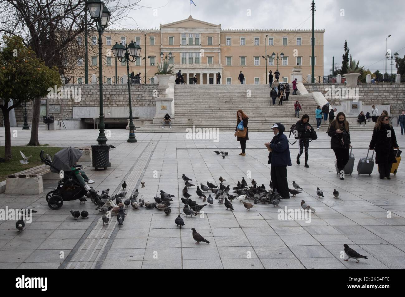 A woman feeds and photographs her child pigeons front of the Greek ...