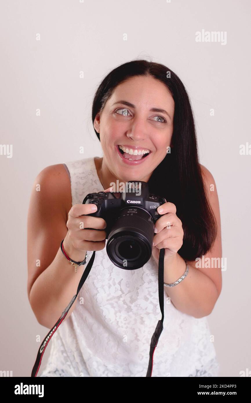 A vertical shot of a smiling Caucasian female photographer holding a ...