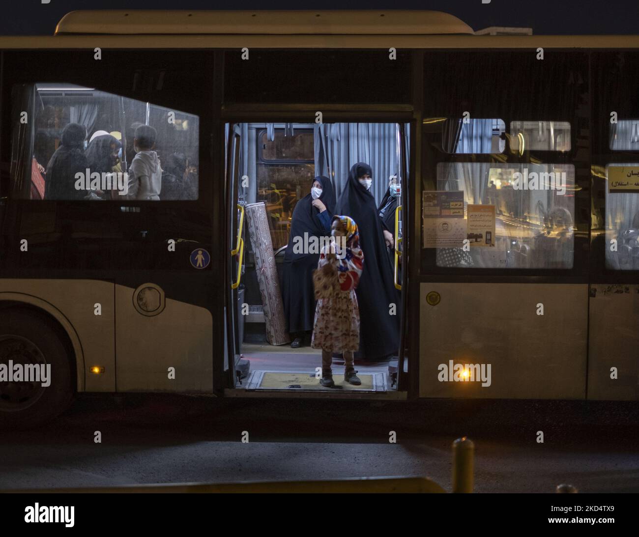 Iranian veiled women stand at a bus near a holy shrine after evening ...