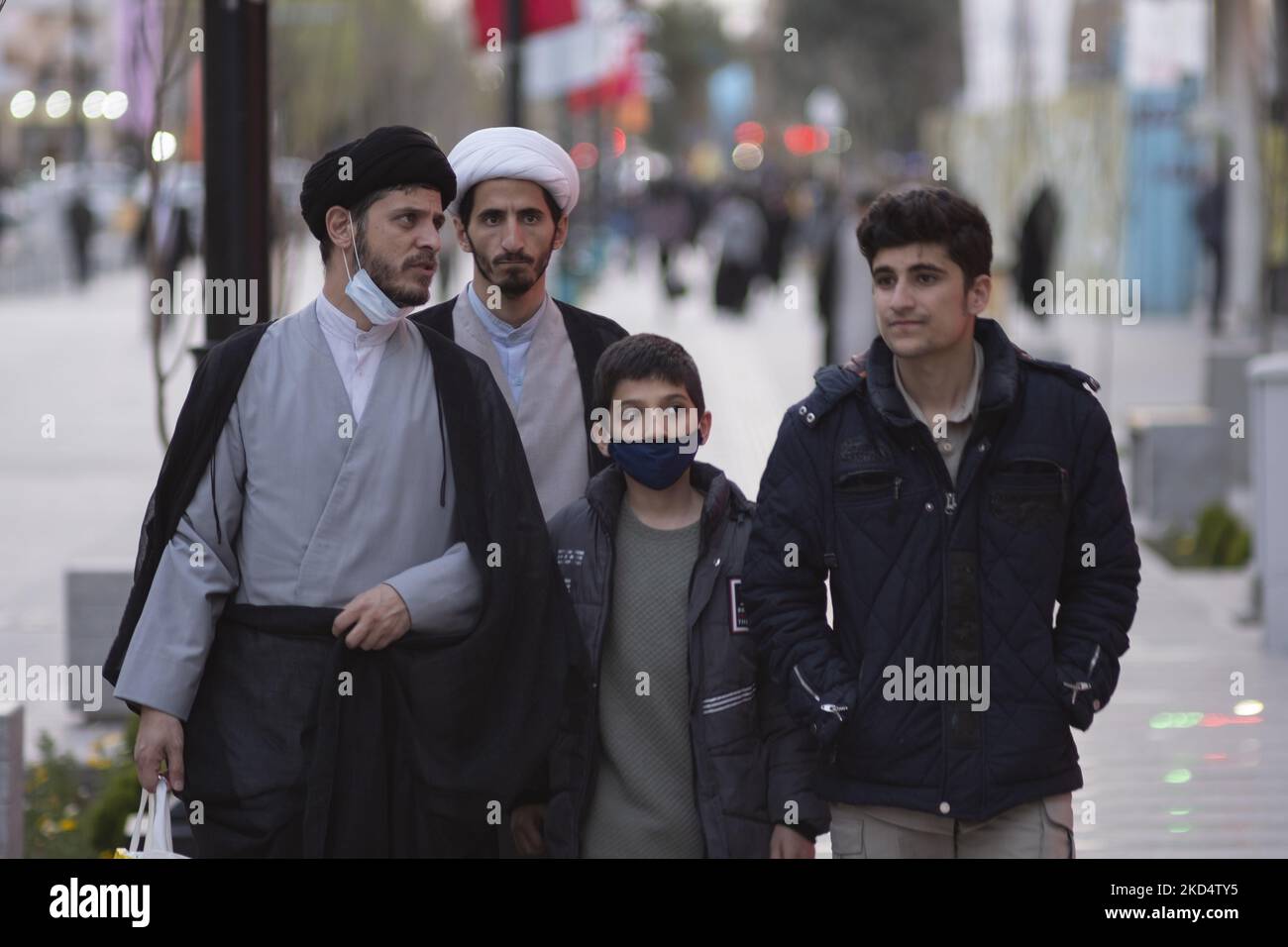 Two clerics and youths walk along a street in the holy city of Qom ...