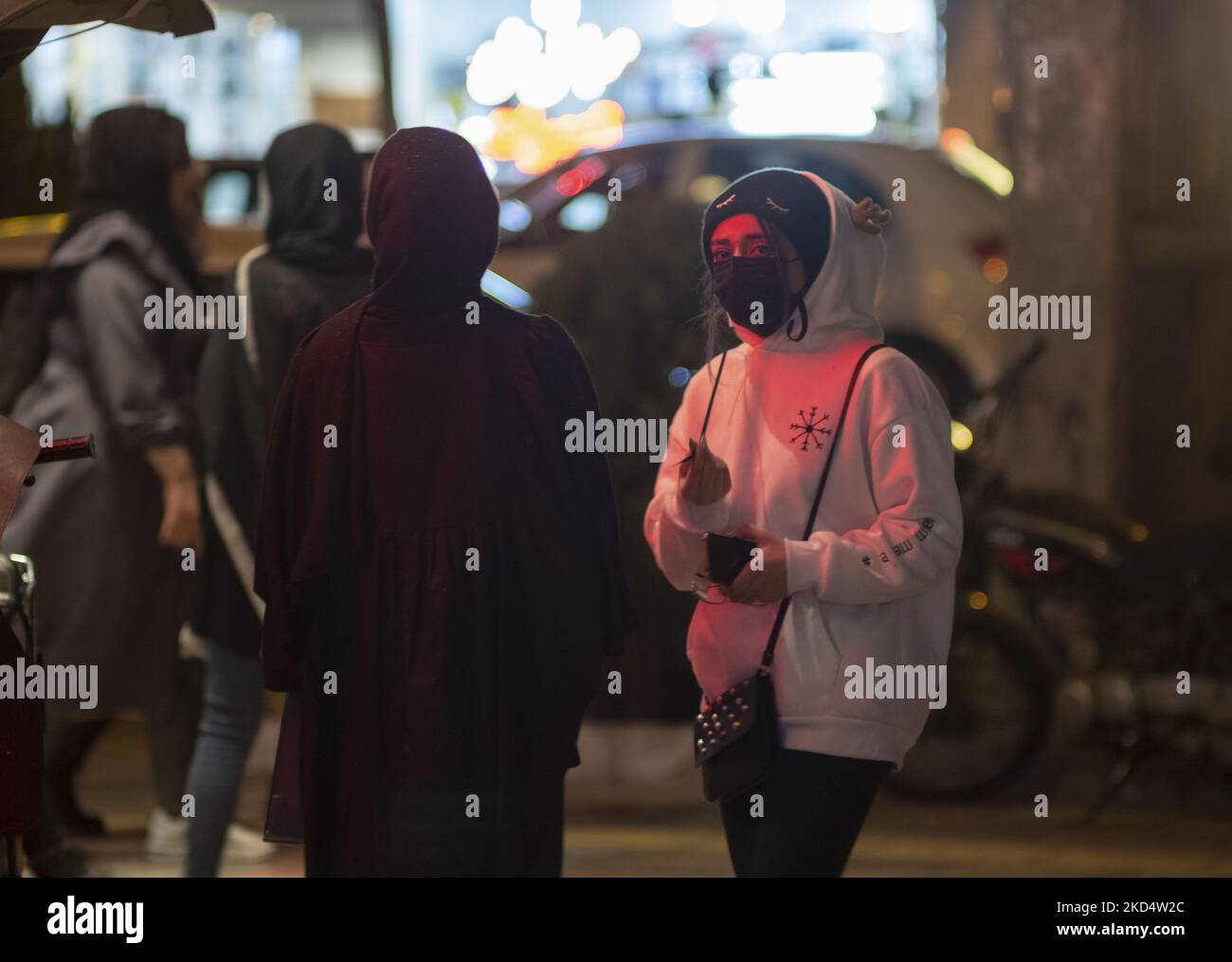 An Iranian young girl wearing a protective face mask looks on while ...