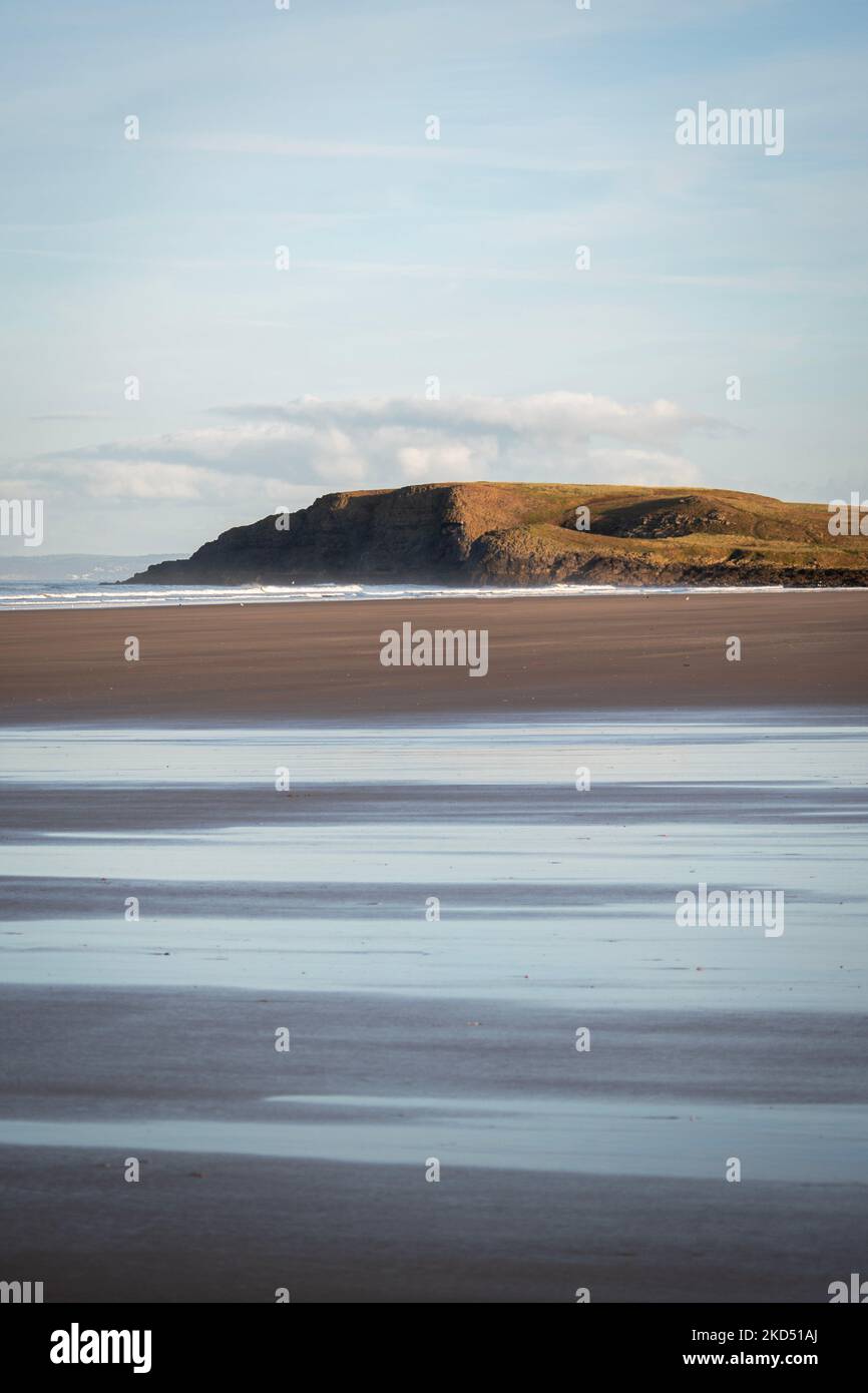 A light blue lake water with green hill in a distance under blue sky ...