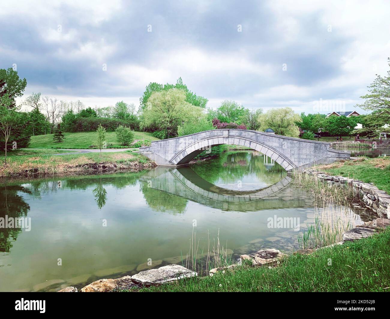 The arched stone bridge with visible reflection on the lake water in ...