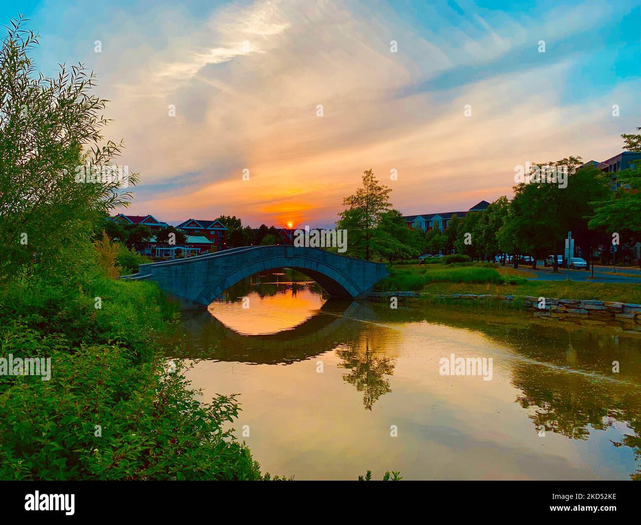 The sun setting over the arched stone bridge in Parc Marcel-Laurin in ...