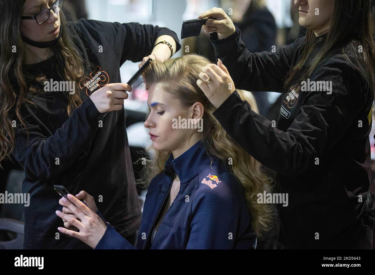 Makeup artists styling a model's hair backstage during the Ukrainian Fashion Week Fall-Winter ...
