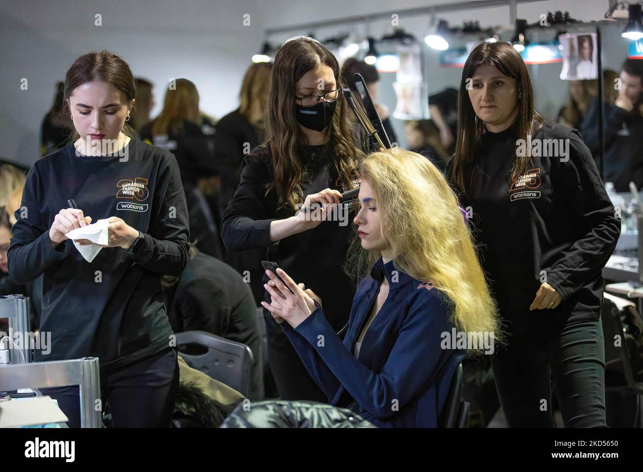 Makeup artists styling a model's hair backstage during the Ukrainian Fashion Week Fall-Winter ...