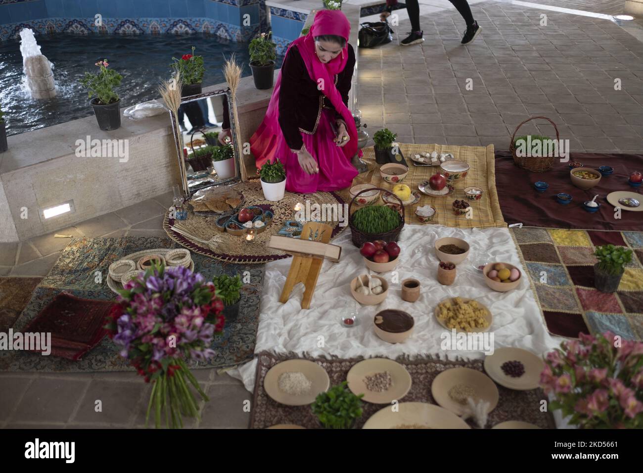An Iranian woman sits next to a Haft-Seen table which is the main ...