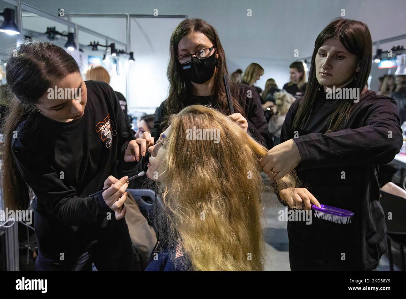 Makeup artists styling a model's hair backstage during the Ukrainian Fashion Week Fall-Winter ...