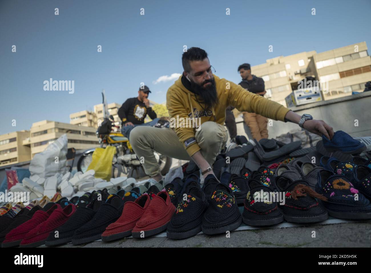 An Iranian vendor adjusts traditional handmade Kurdish shoes, Giveh, on ...