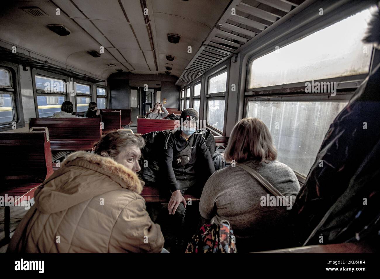 An old man with a facemask waiting in the train. Ukrainian people, war ...