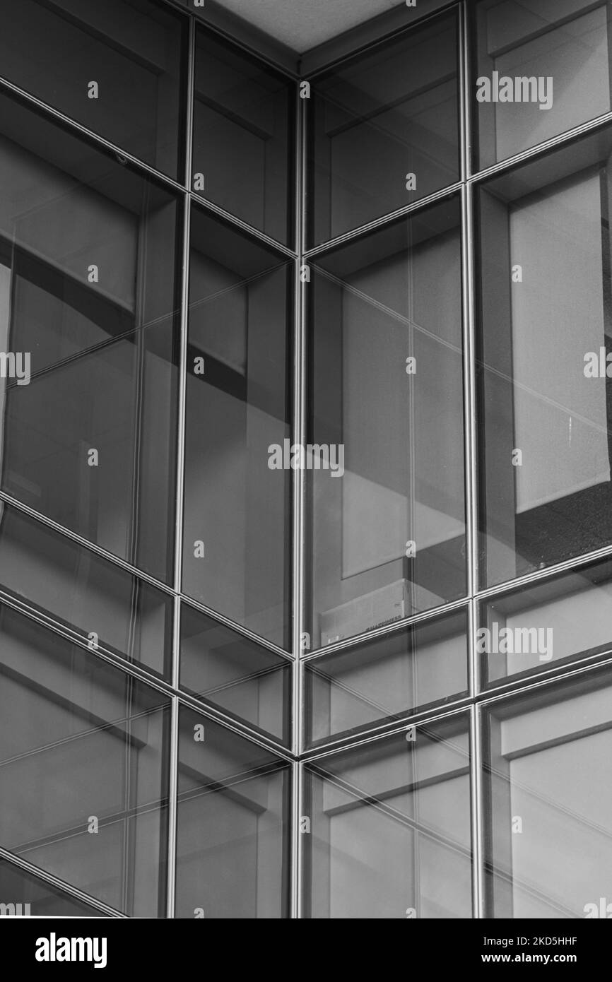 A vertical grayscale of modern office windows with metal railing, glass ...