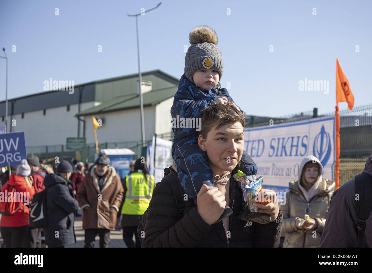A boy carries his little brother, just entered from the border crossing ...