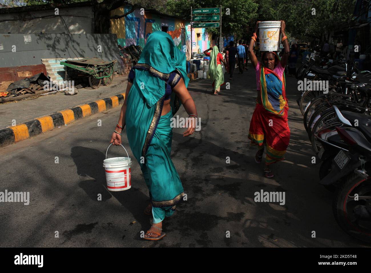 Women carry their containers filled with water from a municipal water ...