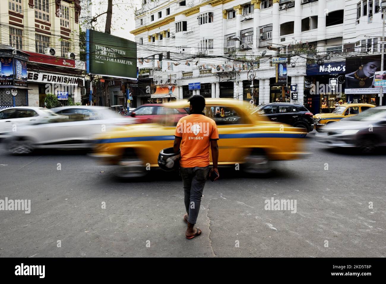 A Swiggy boy waits to cross a busy traffic road in Kolkata, India, 22 ...