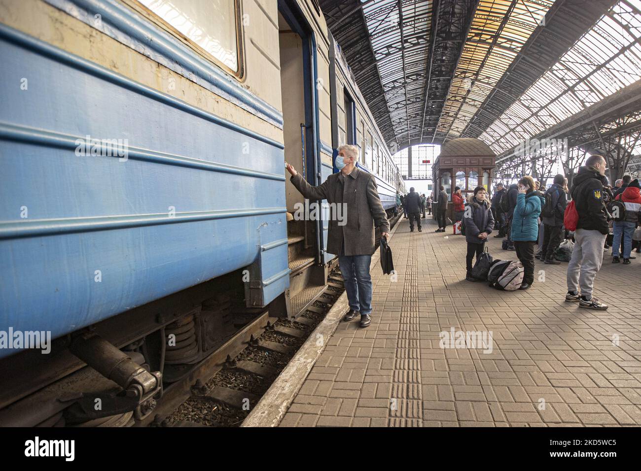 People wait for the train. When the train arrives they move fast to get ...