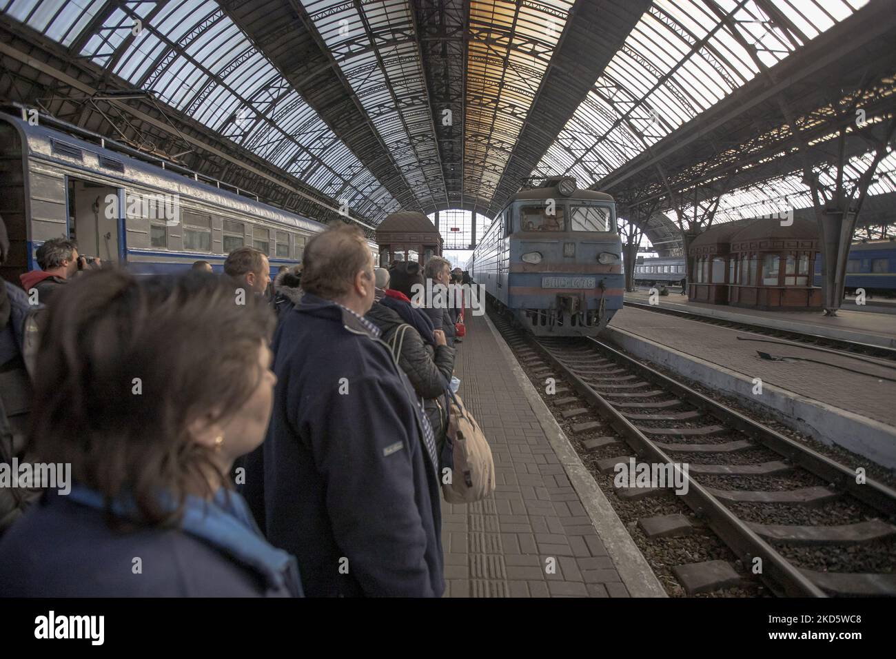 People wait for the train. When the train arrives they move fast to get ...