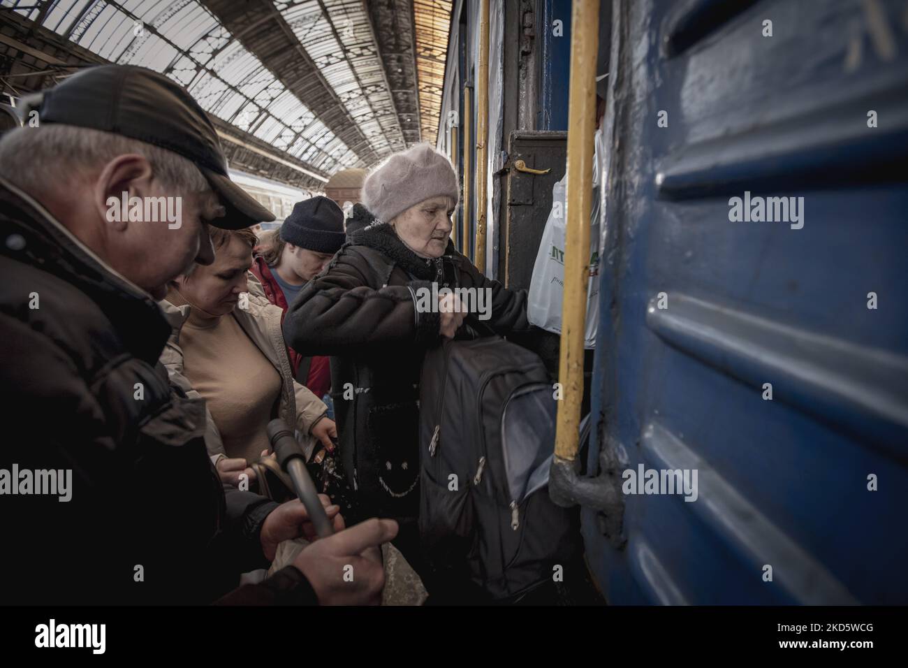 An old woman is boarding with her luggage the train. Ukrainian people ...