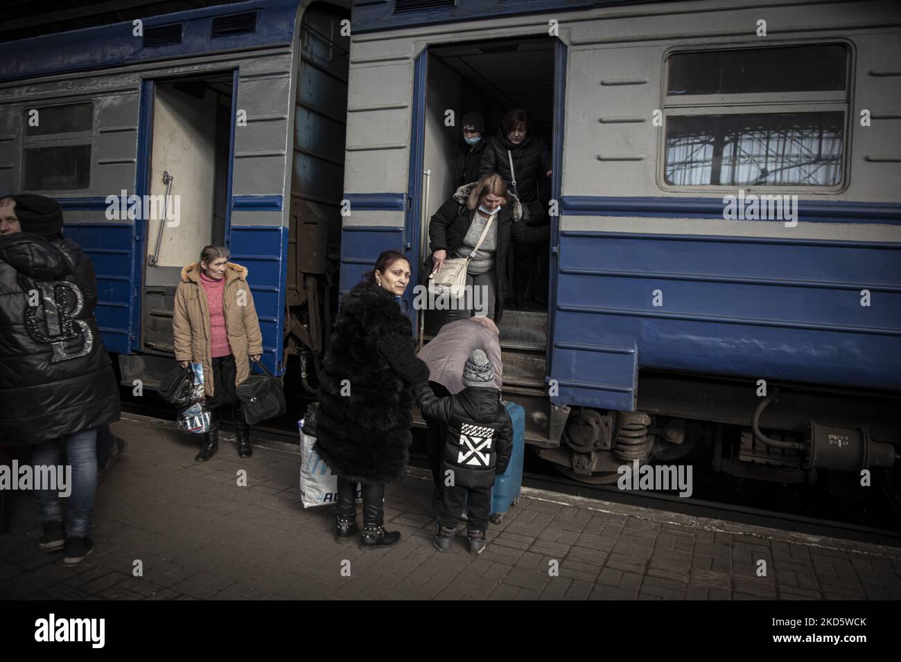A mother holding her child is waiting to board the train. People rush ...