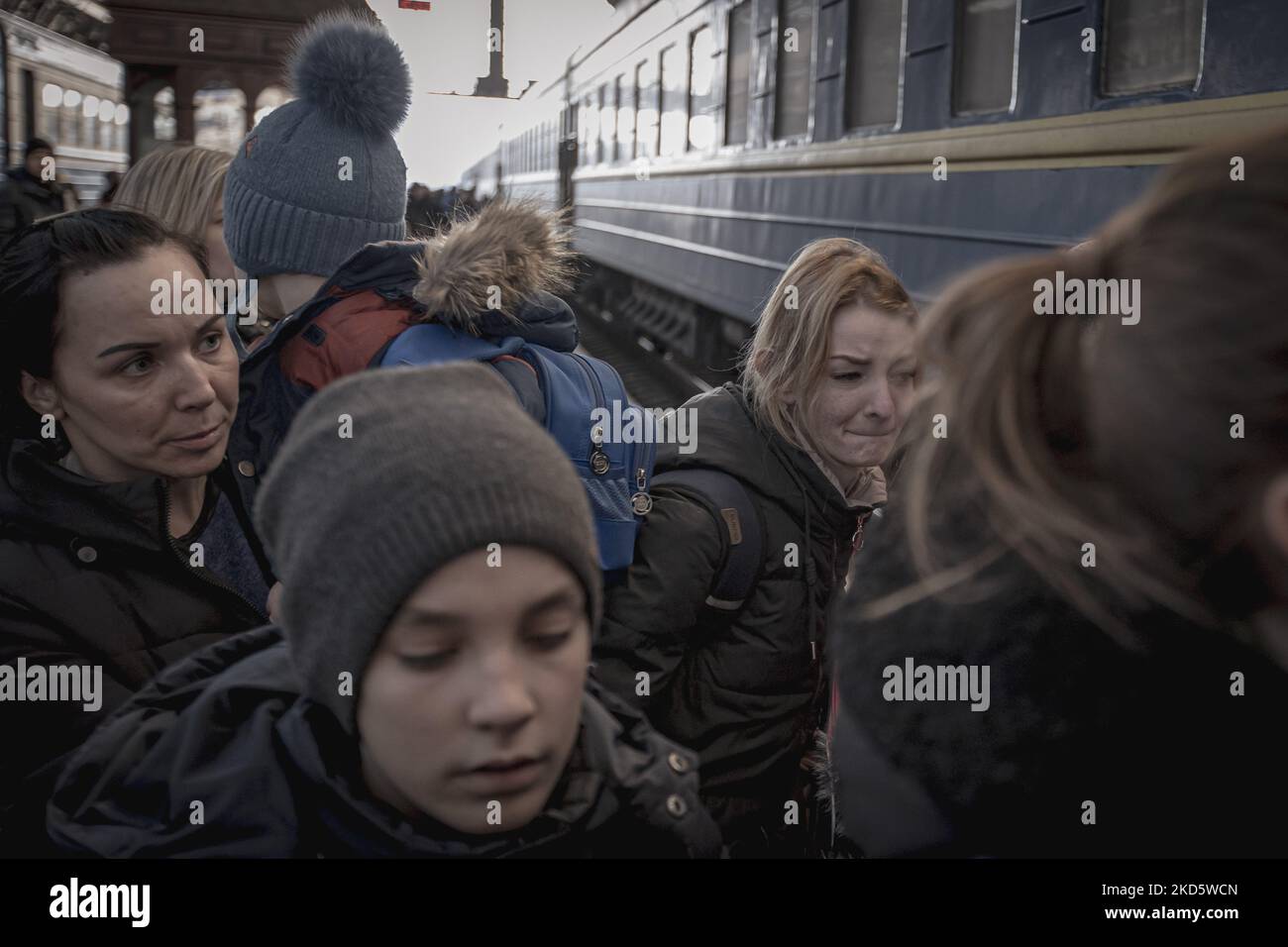 A young woman is crying while she is next to a mother with 2 children ...