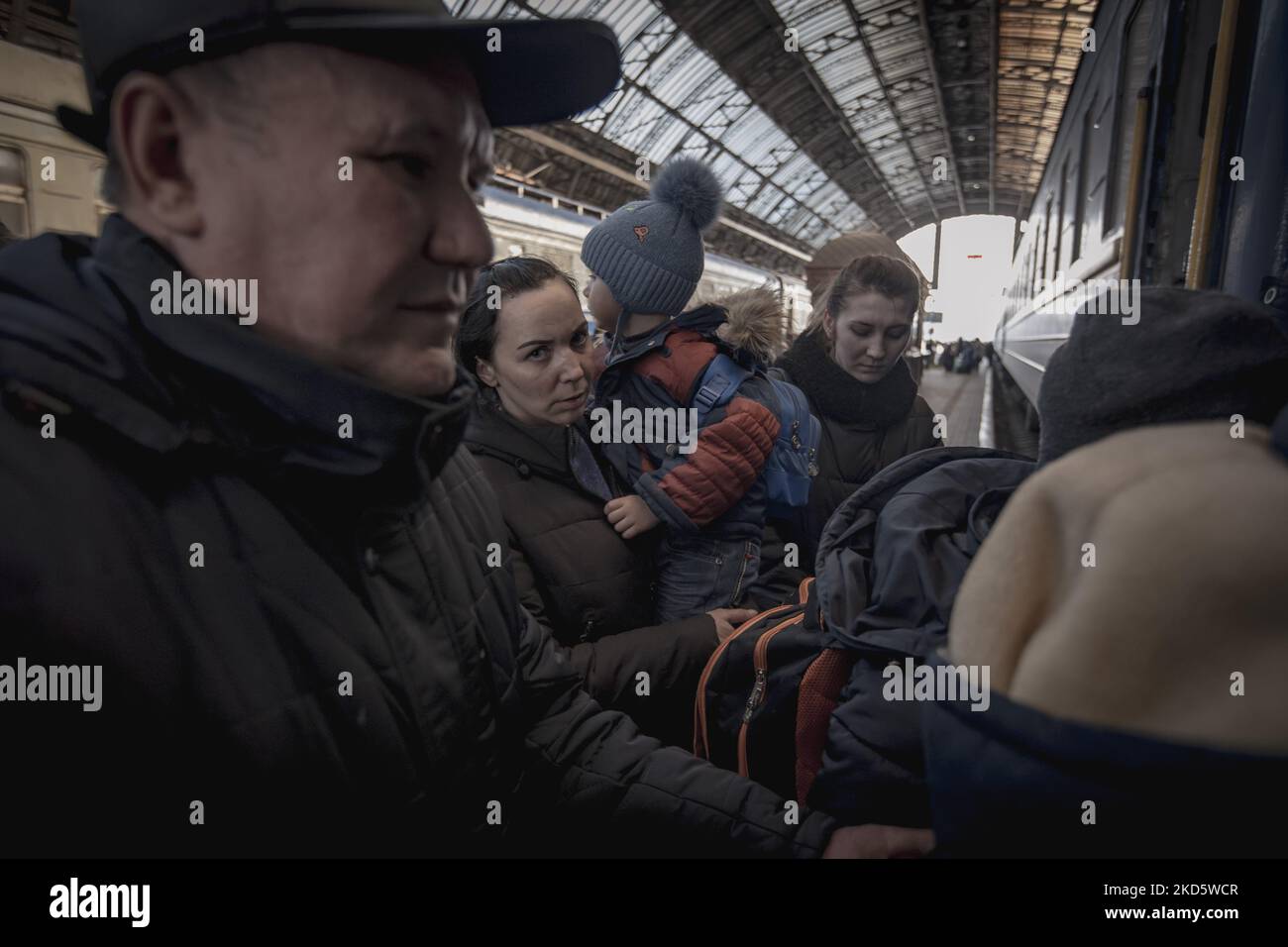 A mother holding her child is waiting to board the train. People rush ...