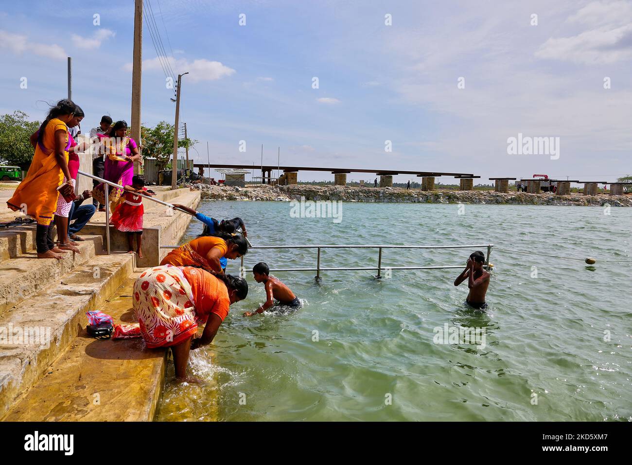 Tamil Hindu devotees take a dip in the water in the sacred water tank ...