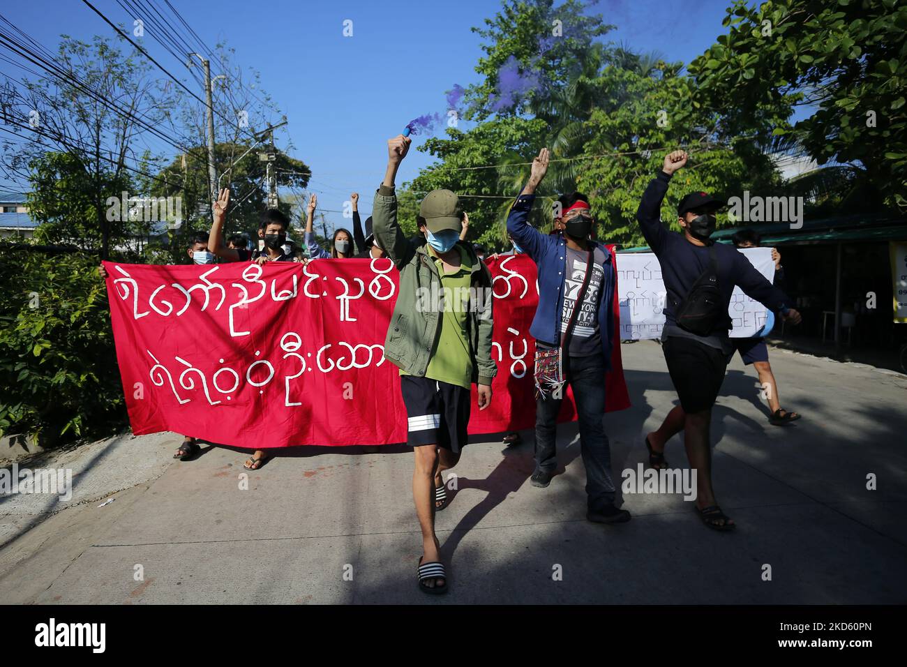 A group of young protesters shout slogans and make the defiant three ...