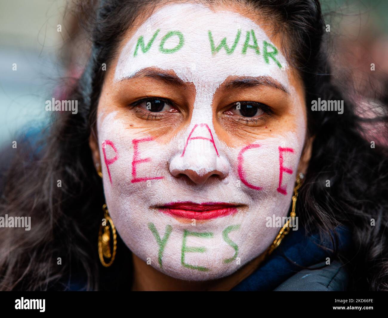 A woman has her face painted with the words peace and no war, during ...